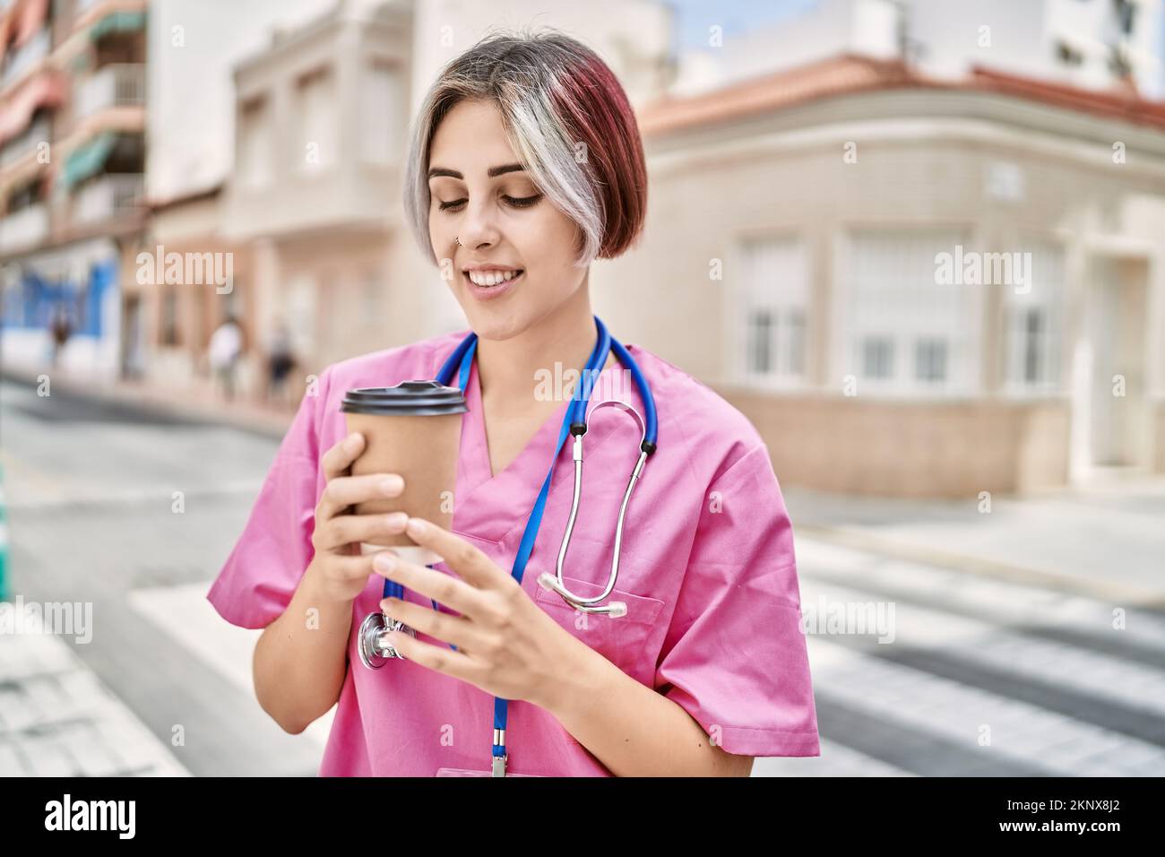 Young caucasian doctor woman smiling happy drinking coffee at the city ...