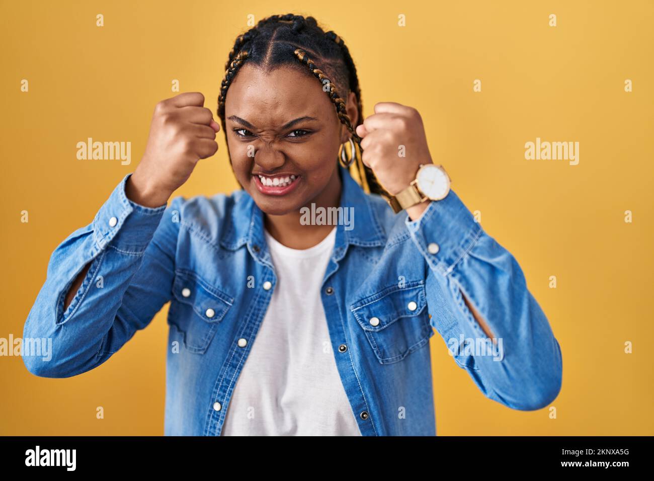 African american woman with braids standing over yellow background ...