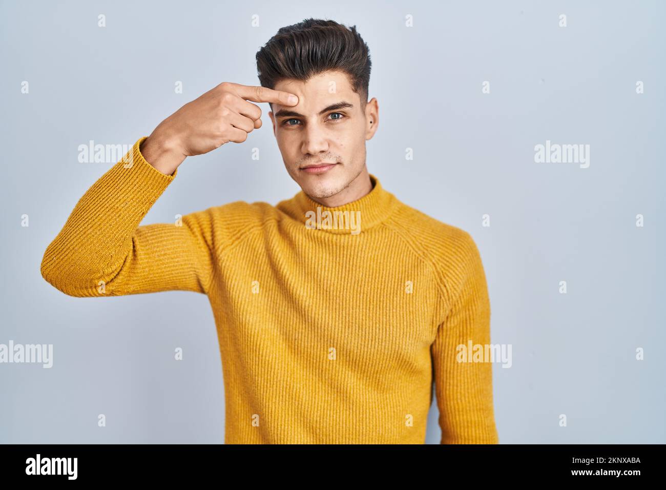 Young hispanic man standing over blue background pointing unhappy to ...