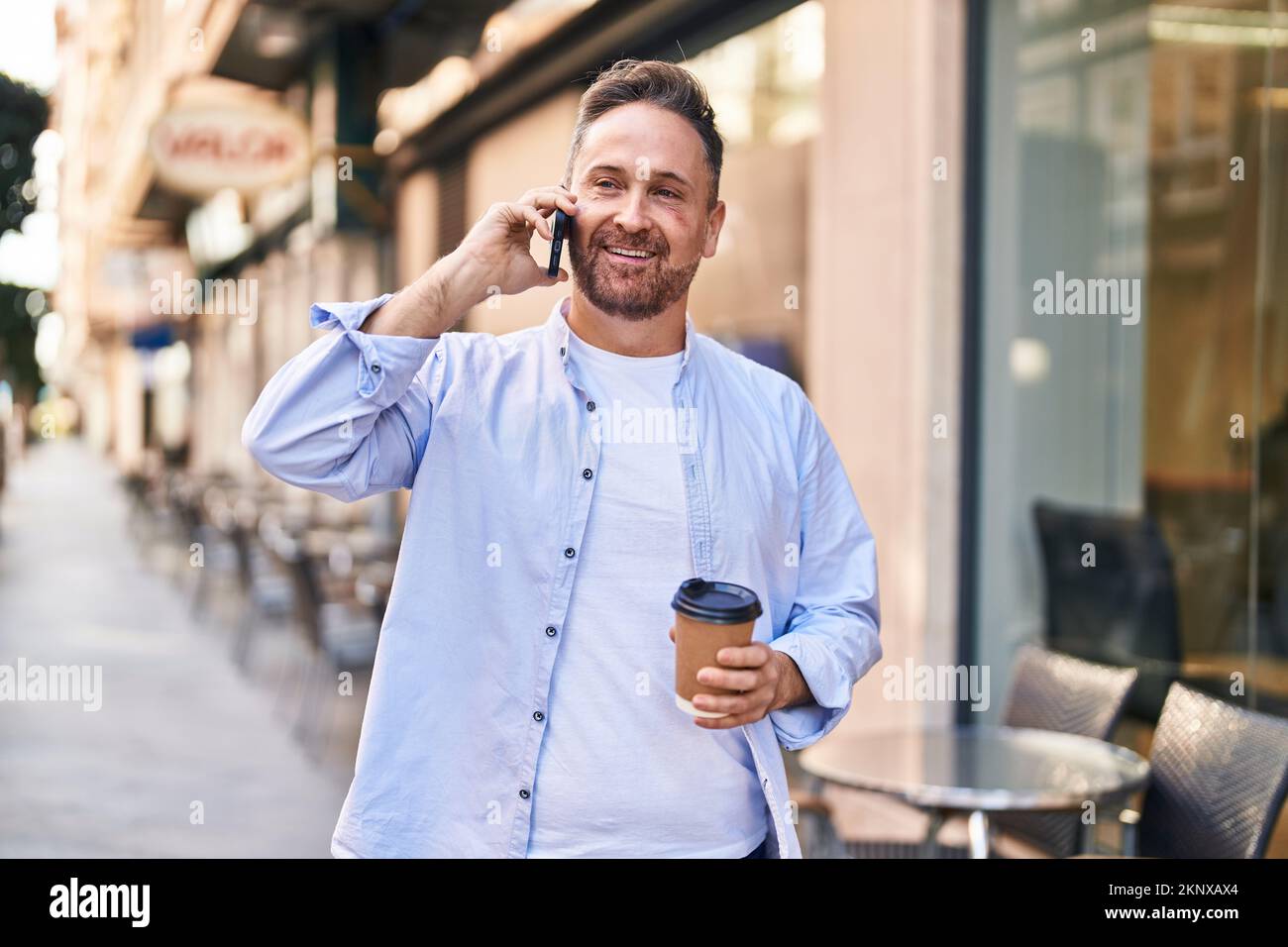 Young caucasian man talking on the smartphone drinking coffee at coffee ...