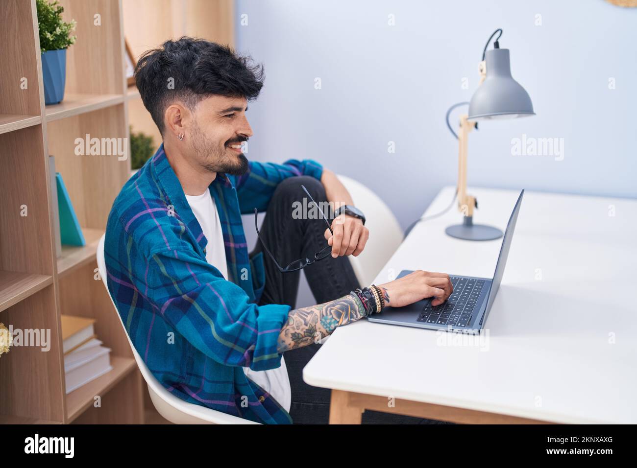 Young hispanic man using laptop sitting on table at home Stock Photo ...