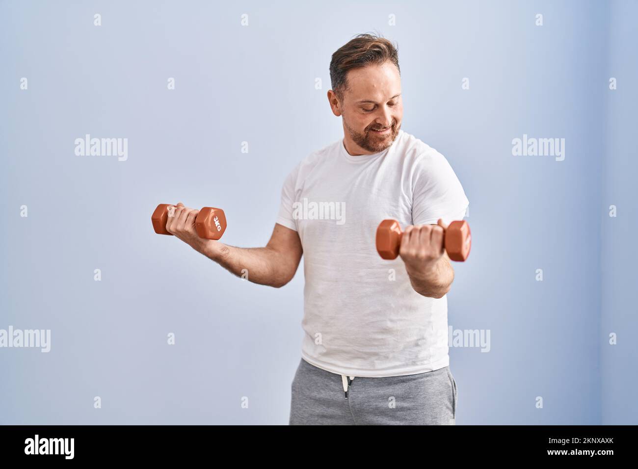 Young caucasian man smiling confident using dumbbells training at sport ...