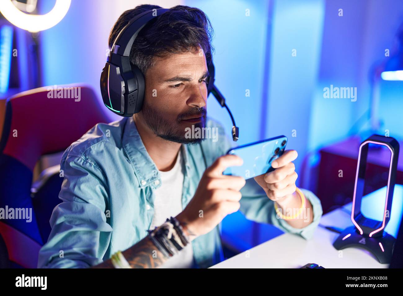 Young hispanic man streamer playing video game using smartphone at ...
