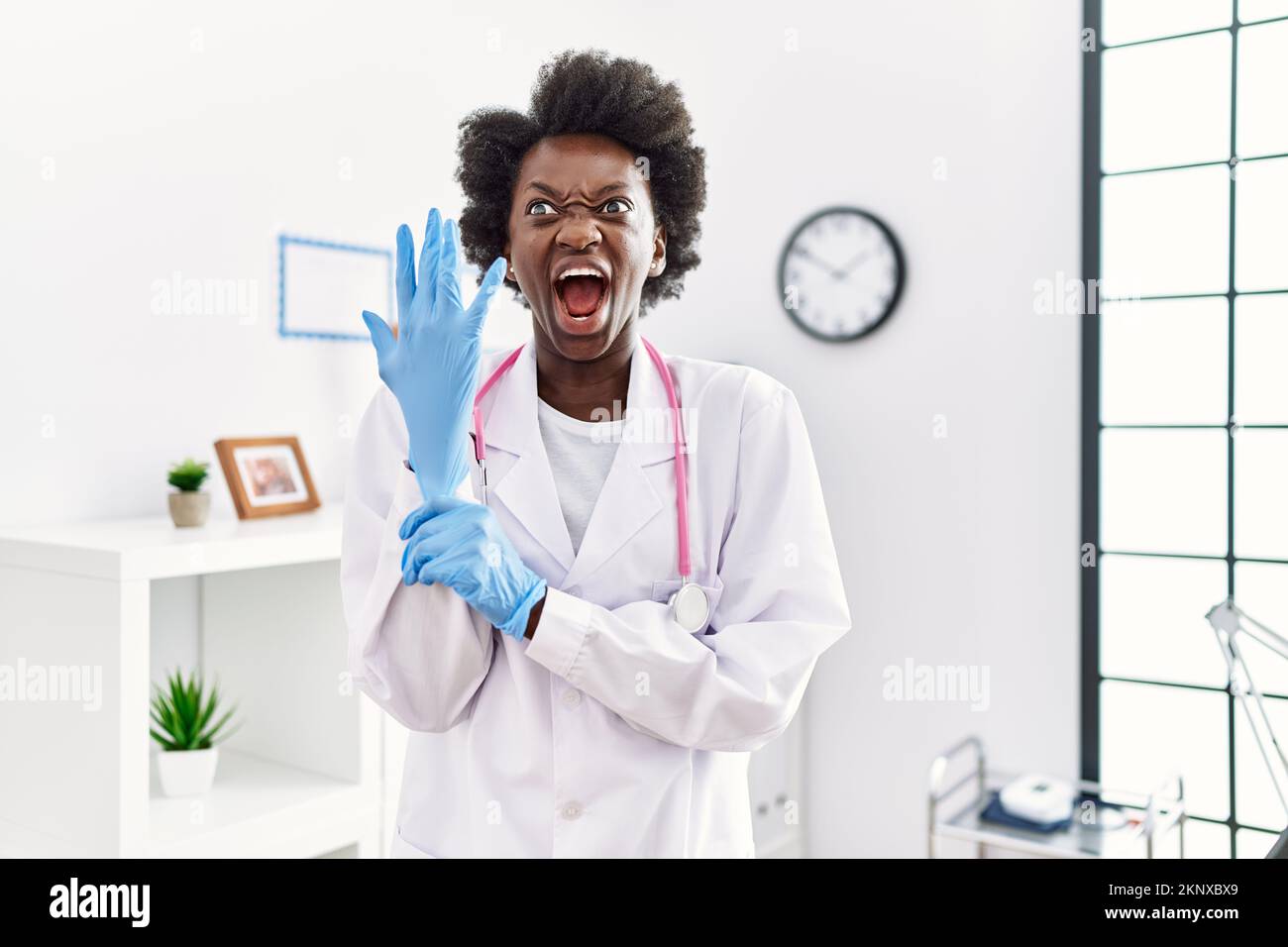 African doctor woman wearing latex gloves at medical clinic angry and ...