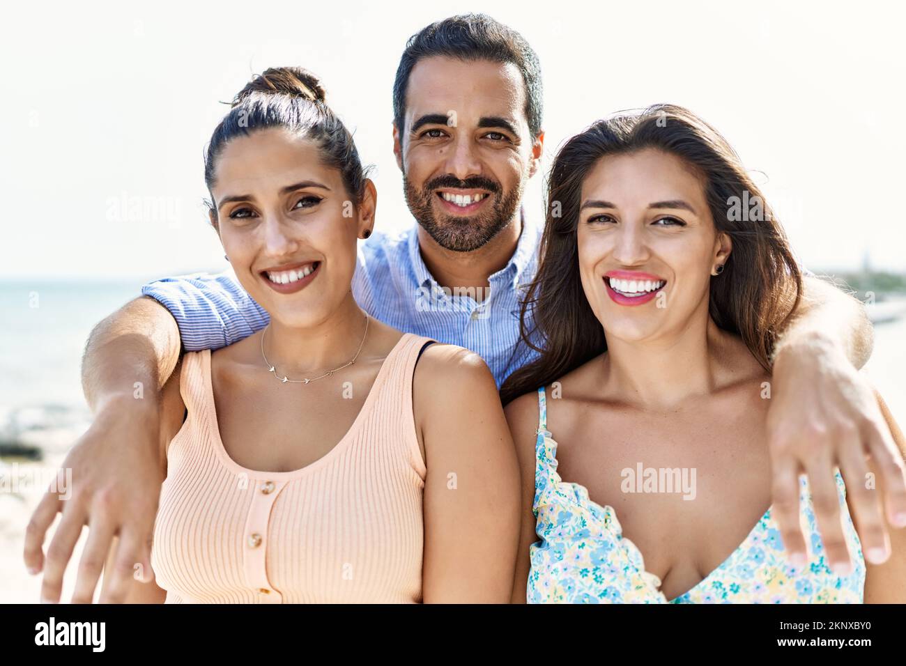 Three young hispanic friends smiling happy and hugging at the beach ...