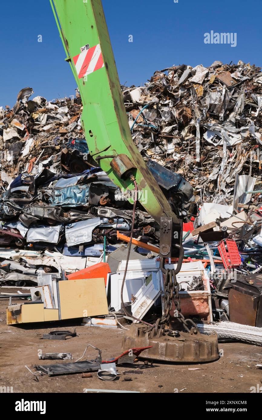 Grappling arm fitted with magnet in front of pile of discarded ...