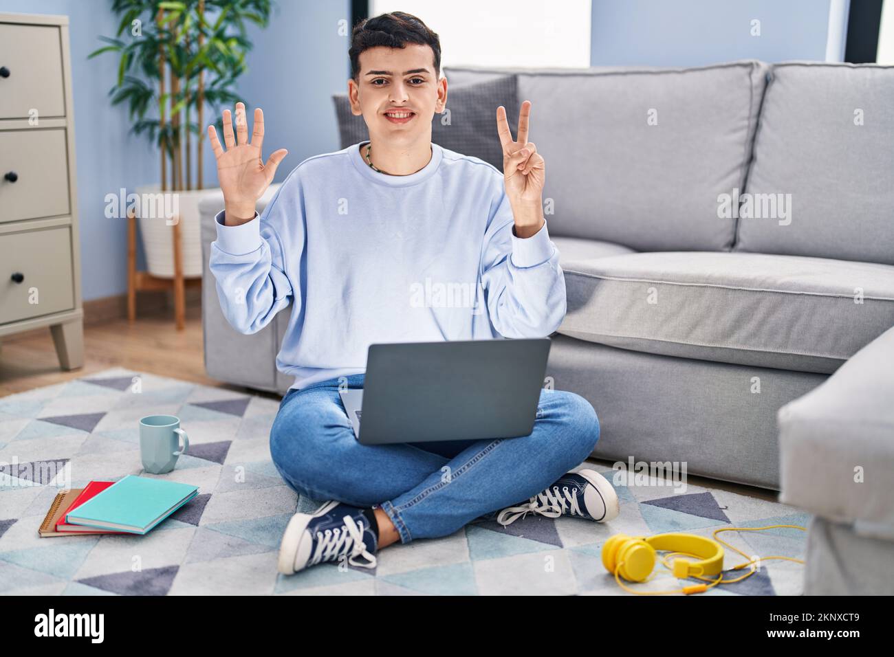 Non binary person studying using computer laptop sitting on the floor ...