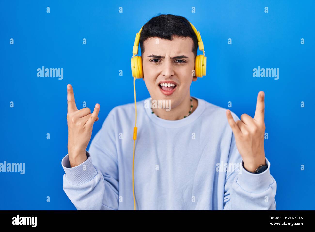 Non binary person listening to music using headphones shouting with ...