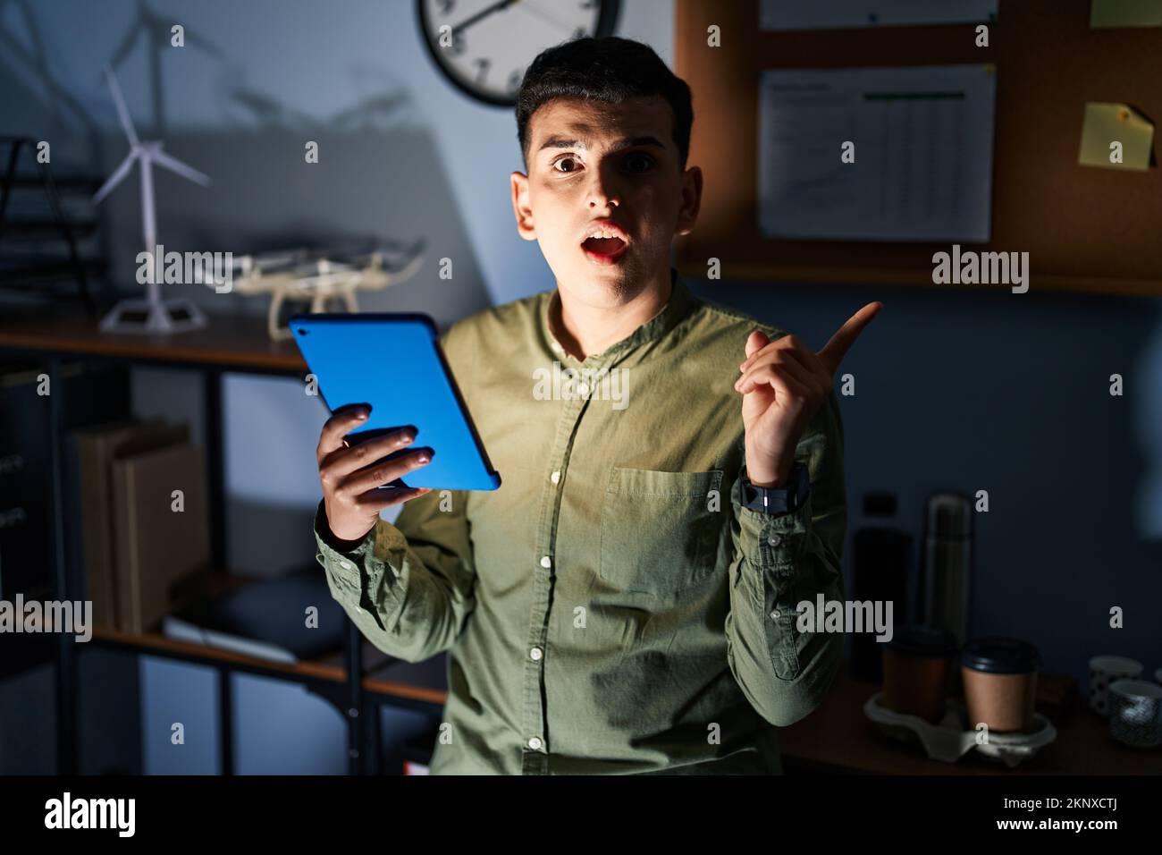 Non binary person using touchpad device at night surprised pointing ...