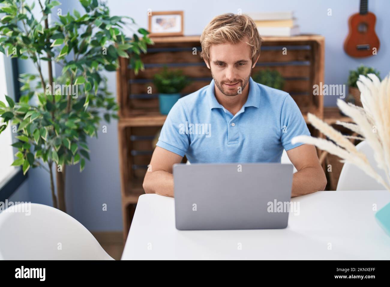 Young man using laptop sitting on table at home Stock Photo - Alamy