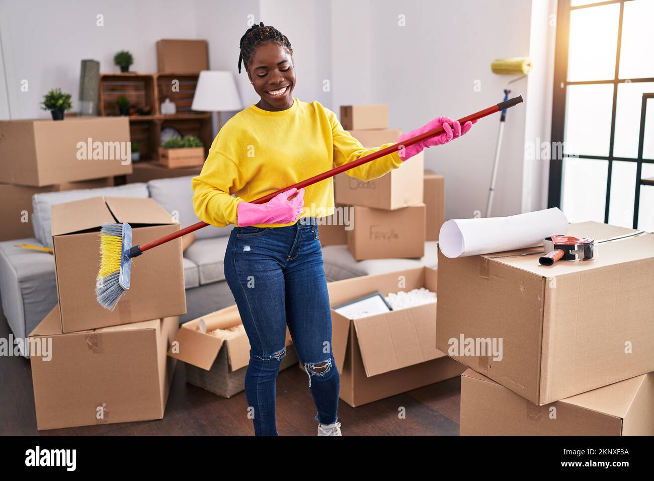 African american woman playing mop as a guitar cleaning at new home ...