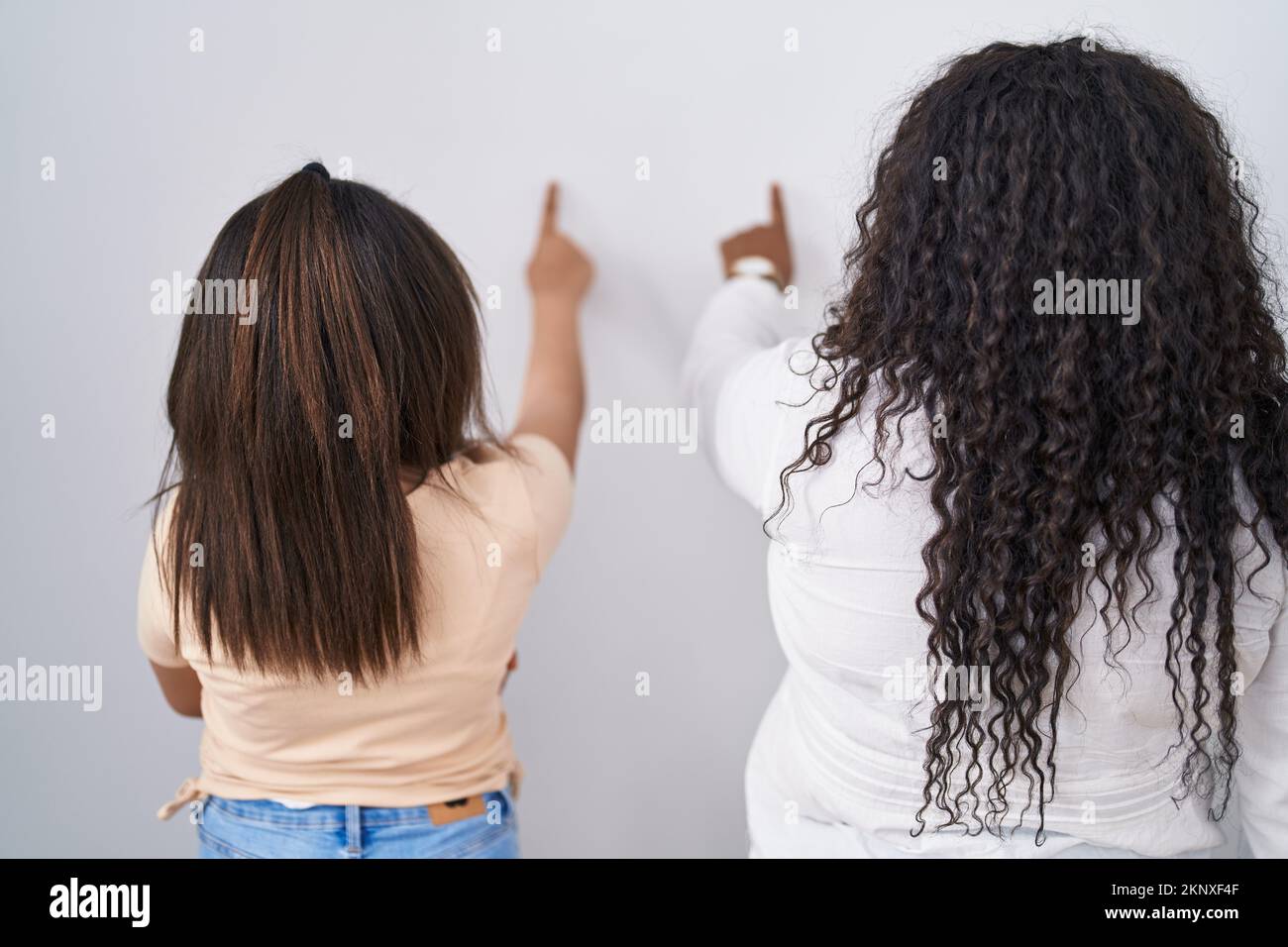 Mother and young daughter standing over white background posing ...
