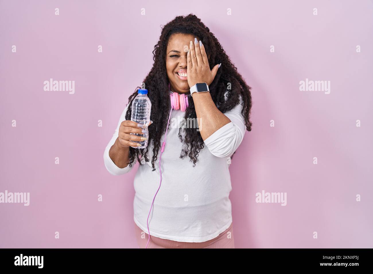 Plus size hispanic woman wearing sportswear and headphones covering one ...