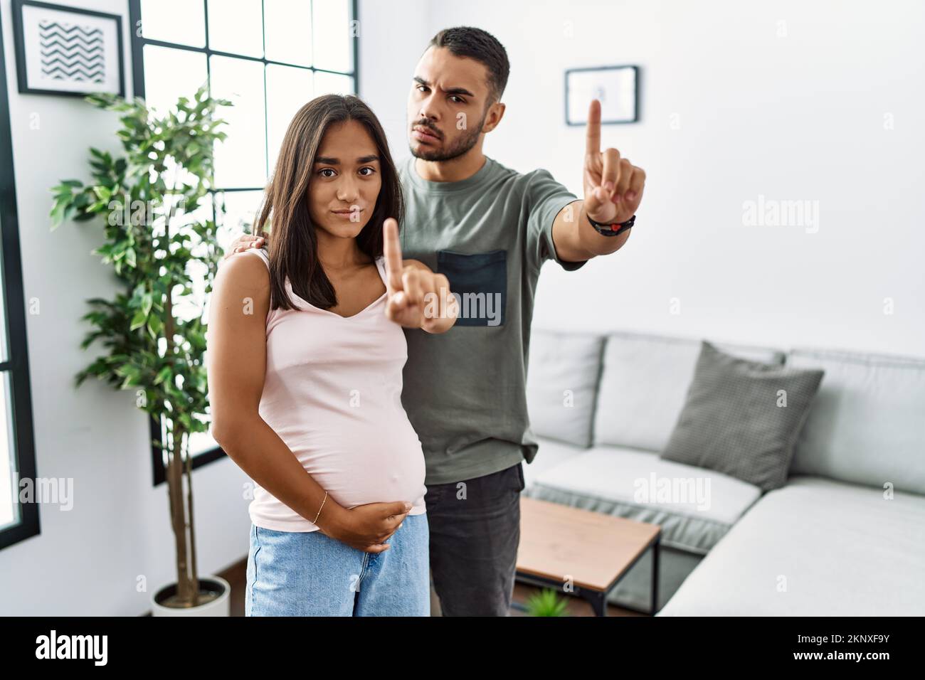 Young interracial couple expecting a baby, touching pregnant belly ...