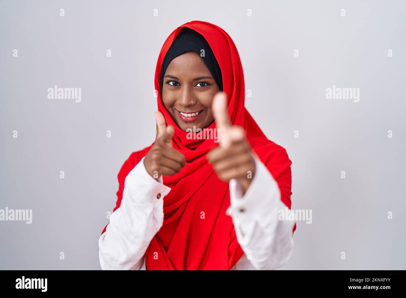 Young arab woman wearing traditional islamic hijab scarf pointing ...