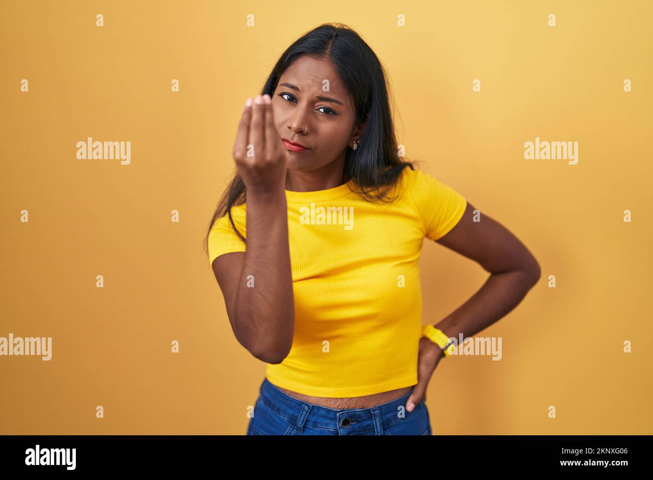 Young indian woman standing over yellow background doing italian ...