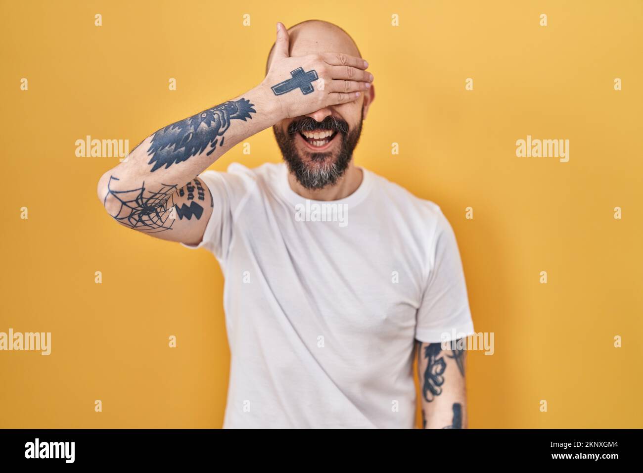 Young hispanic man with tattoos standing over yellow background smiling ...