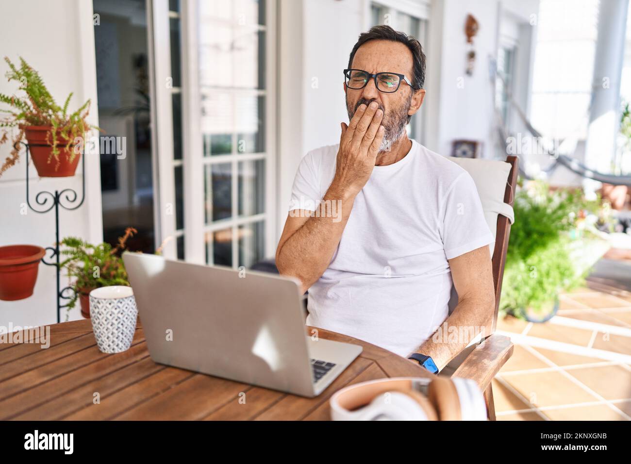 Middle age man using computer laptop at home bored yawning tired ...