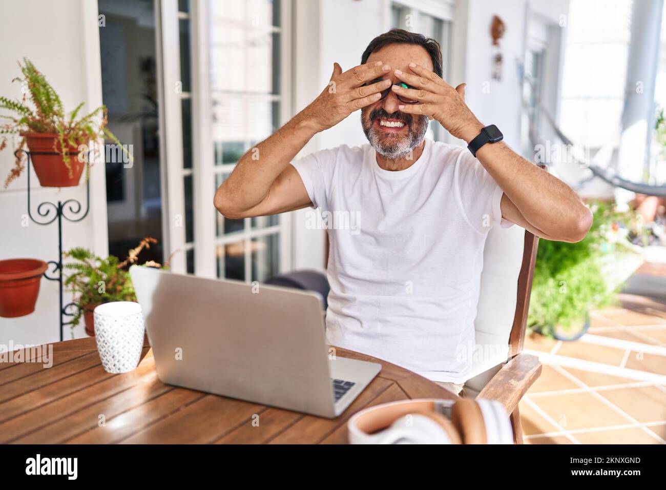 Middle age man using computer laptop at home covering eyes with hands ...