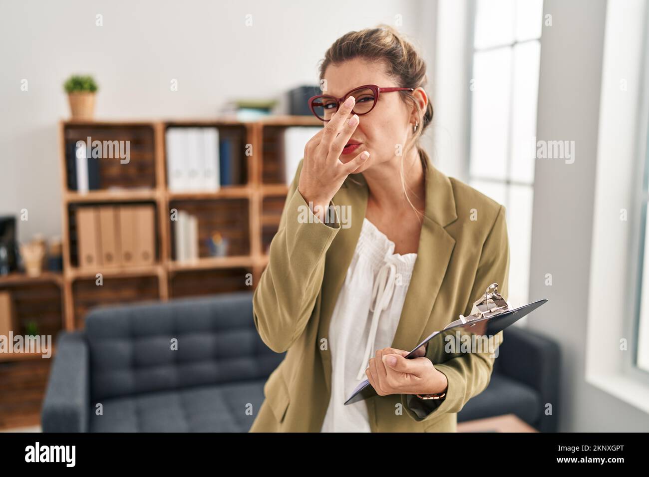 Young woman working at consultation office smelling something stinky ...