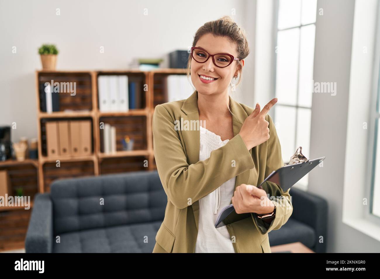 Young woman working at consultation office pointing with hand finger to ...