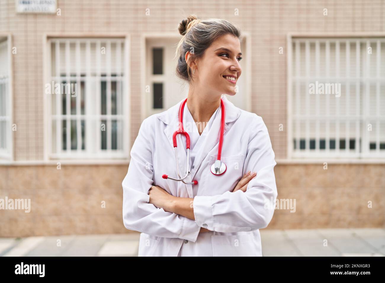 Young blonde woman wearing doctor uniform standing with arms crossed ...