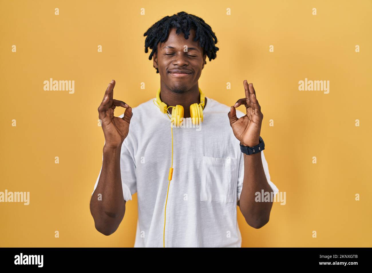 Young african man with dreadlocks standing over yellow background ...