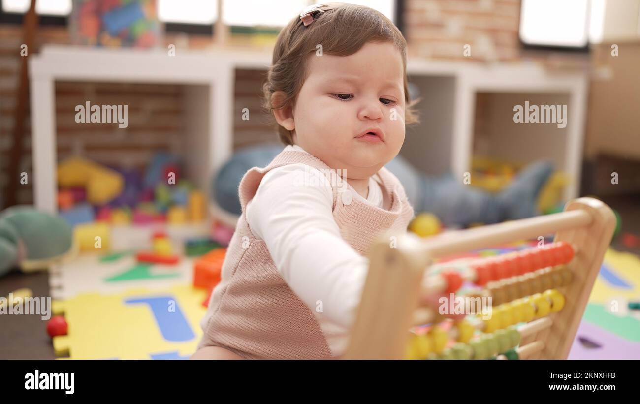 Adorable toddler playing with abacus sitting on floor at kindergarten ...