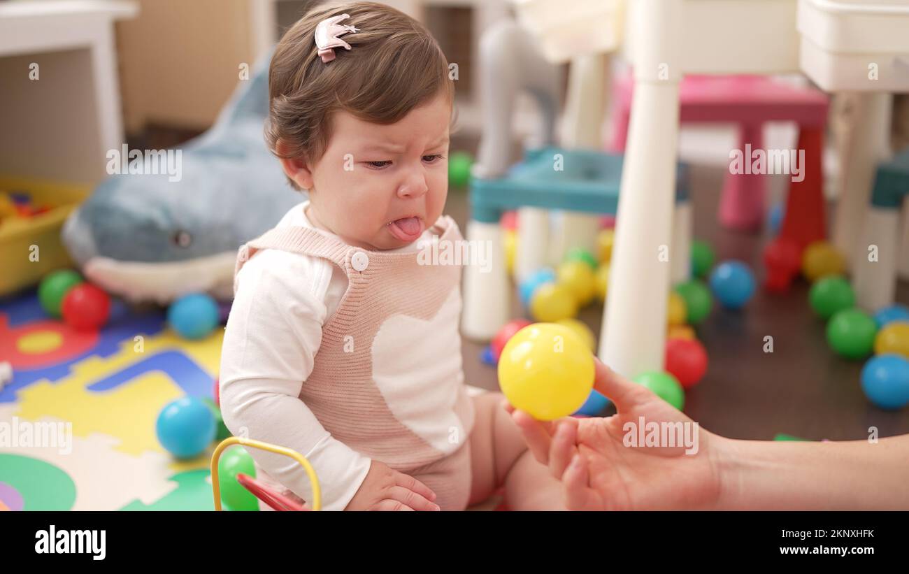 Adorable toddler sitting on floor looking ball crying at kindergarten ...