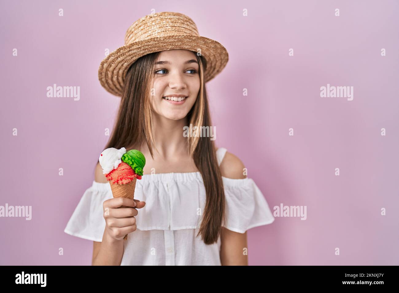 Teenager girl holding ice cream looking away to side with smile on face ...