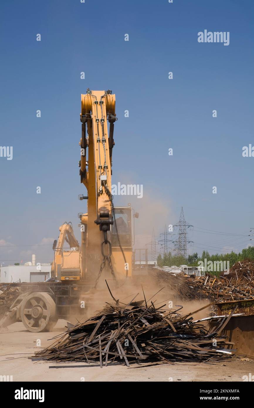 Material handler fitted with a magnet used to move a pile of ferous ...