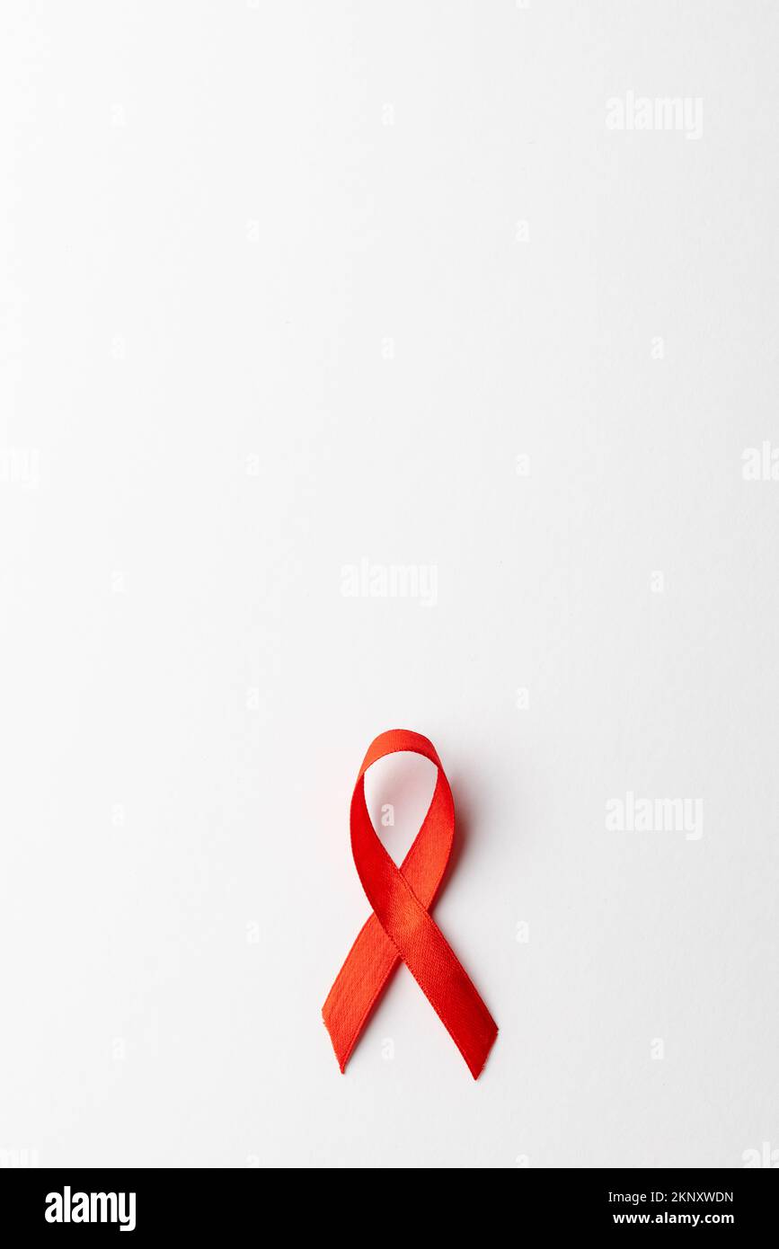 Vertical composition of red ribbon for hiv or aids awareness, on white background with copy ...