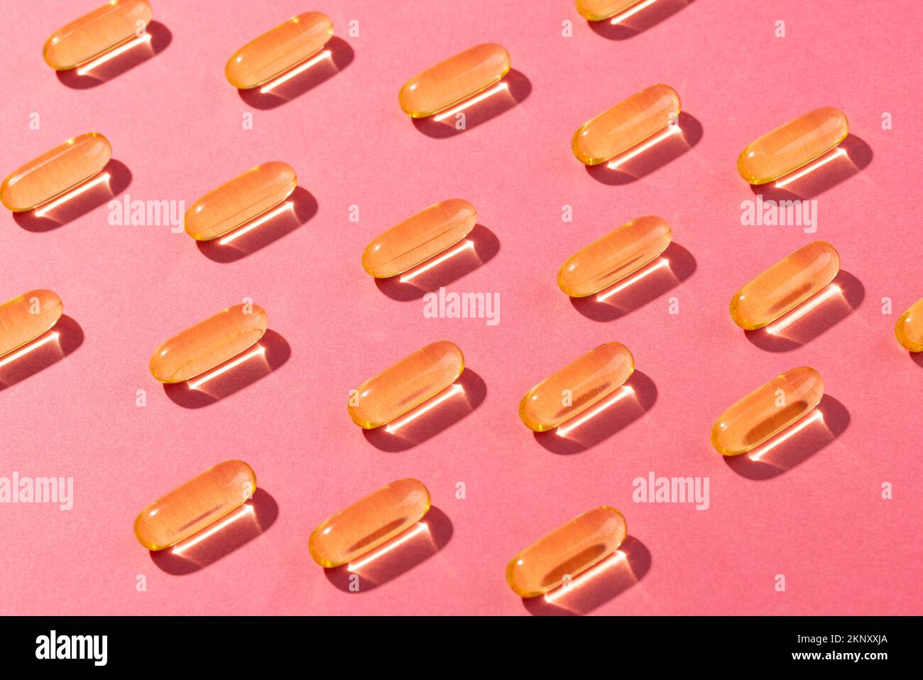 Composition of oil capsules arranged in rows on pink background Stock ...
