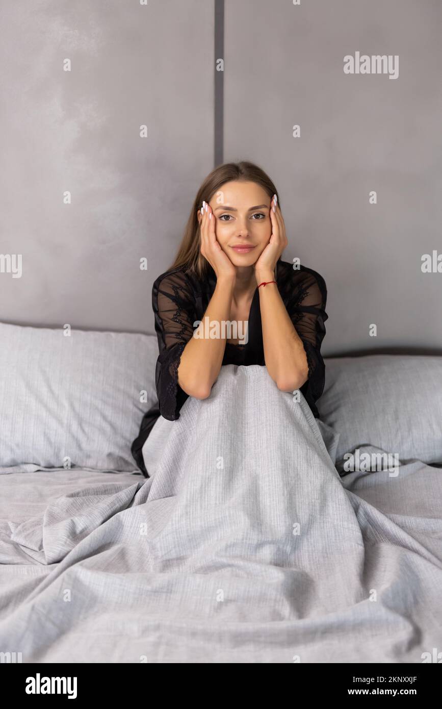 Young beautiful woman sitting on bed at home Stock Photo - Alamy