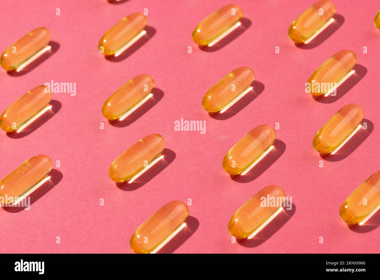 Composition of oil capsules arranged in rows on pink background Stock ...