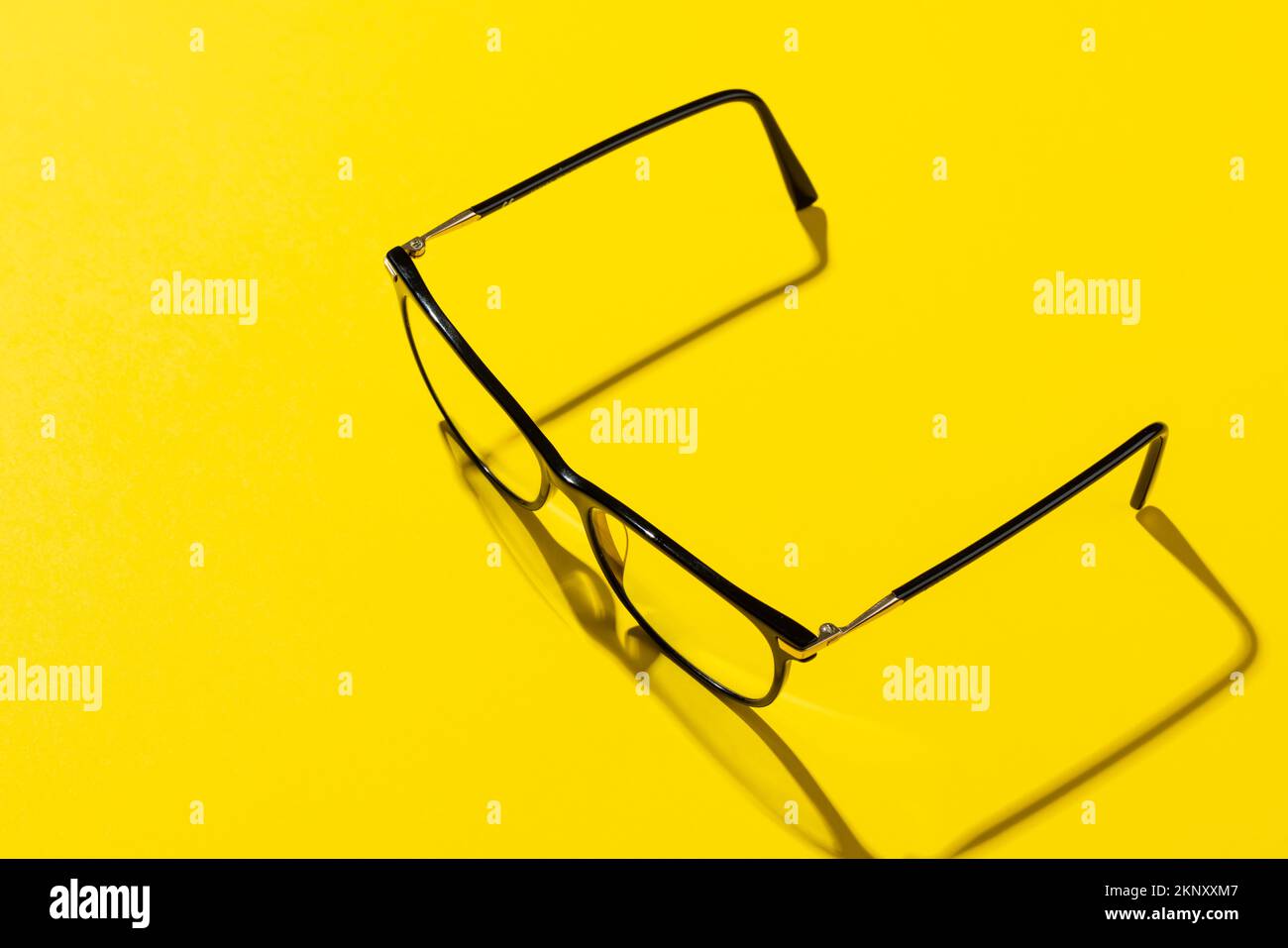 High Angle Composition Of Pair Of Glasses And Shadow On Yellow Background With Copy Space Stock