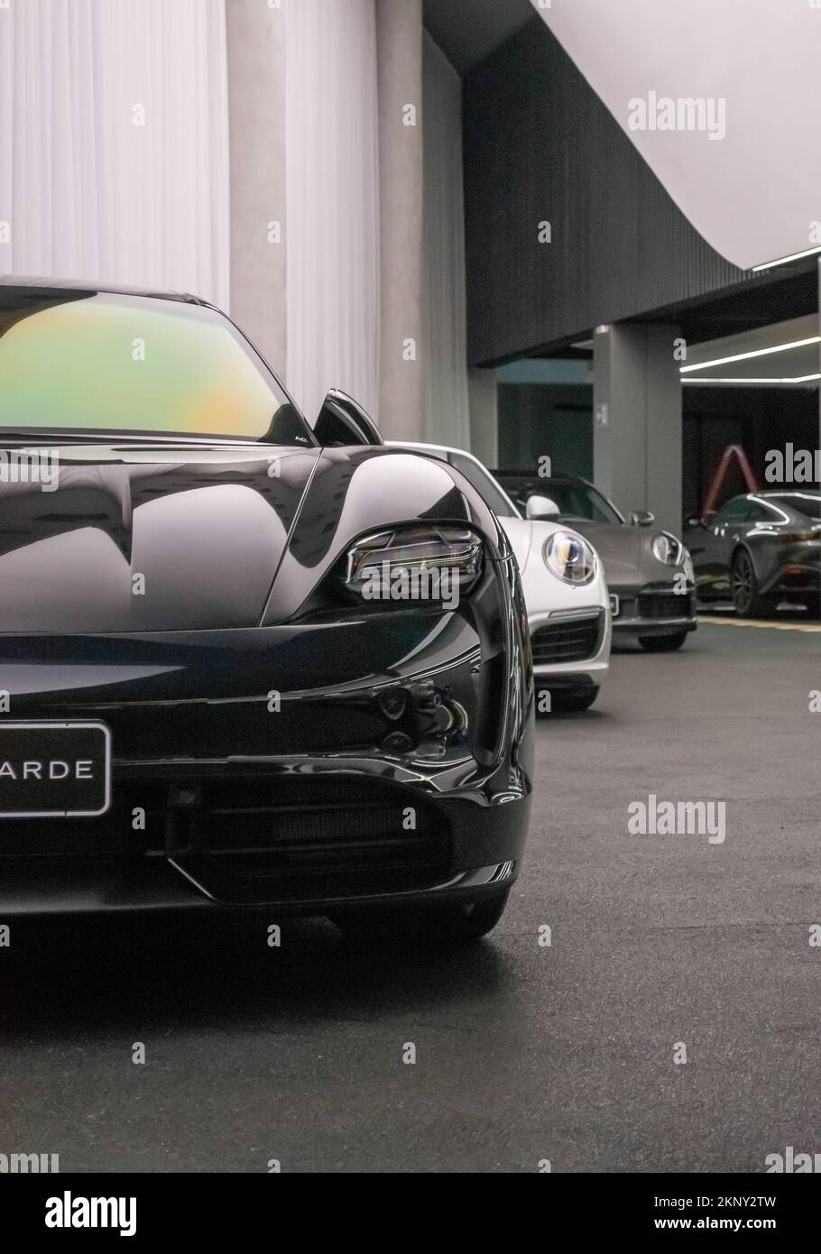 A vertical shot of a triple Porsche line up with a Black Taycan, a ...