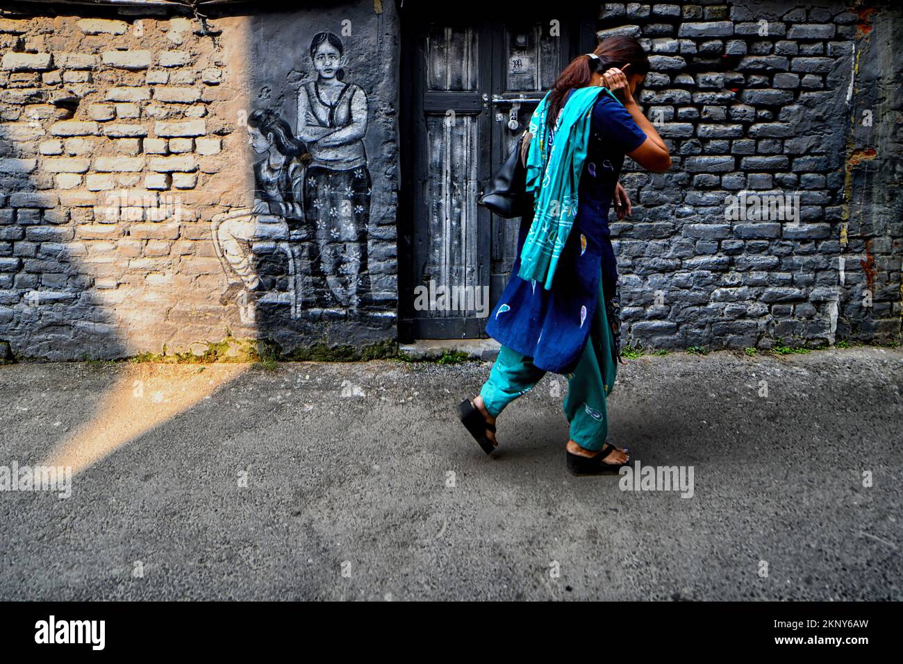 Kolkata, India. 26th Nov, 2022. A woman walks past graffiti mural ...