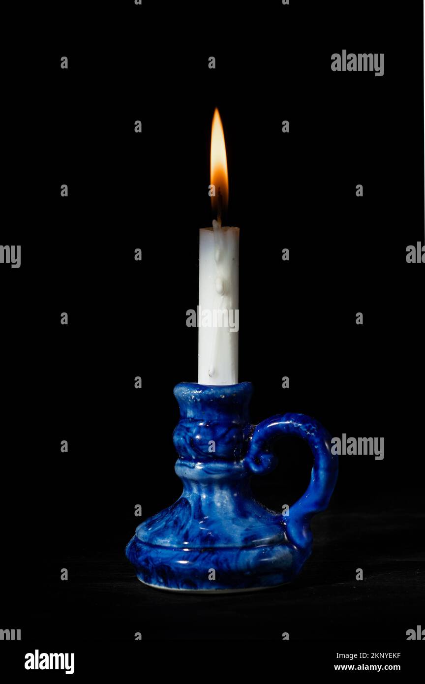 burning candle on candlesticks on a black background Stock Photo - Alamy