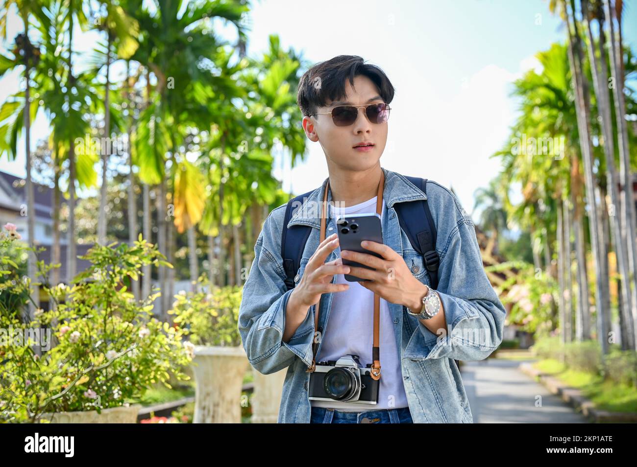 Handsome young Asian male tourist using his smartphone, using map application while strolling ...