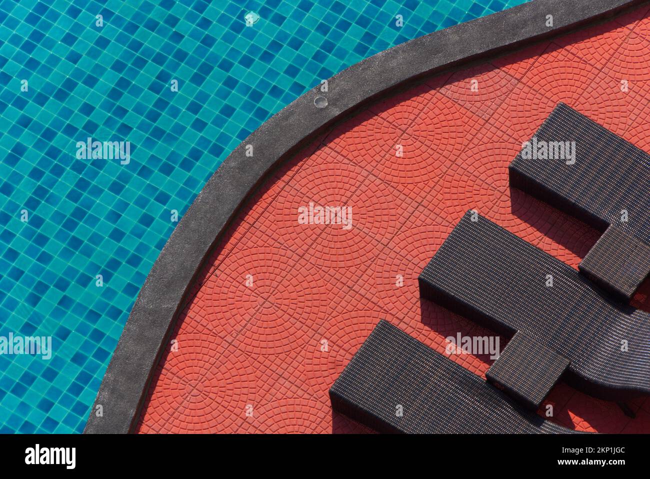 Abstract swimming pool and sun lounger above view with red tiles at a ...