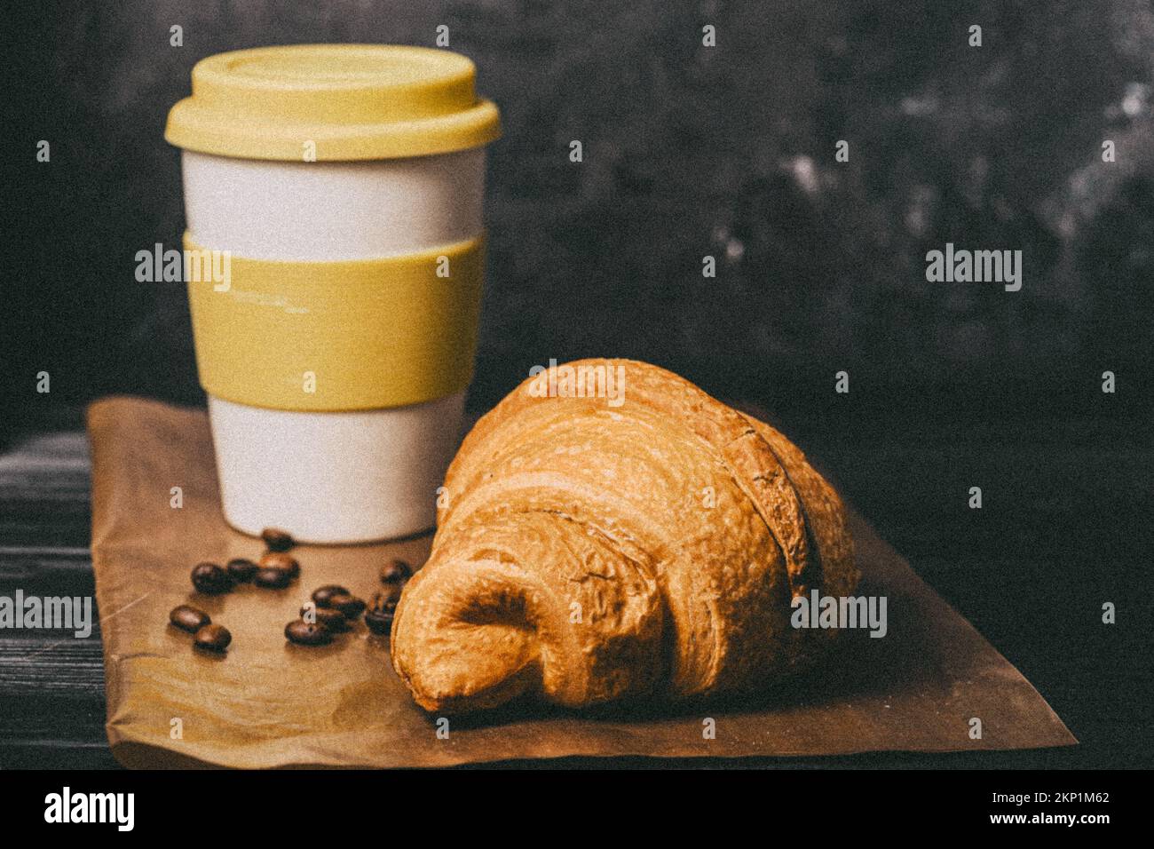 croissant with a mug of coffee on a dark background. retro style with ...