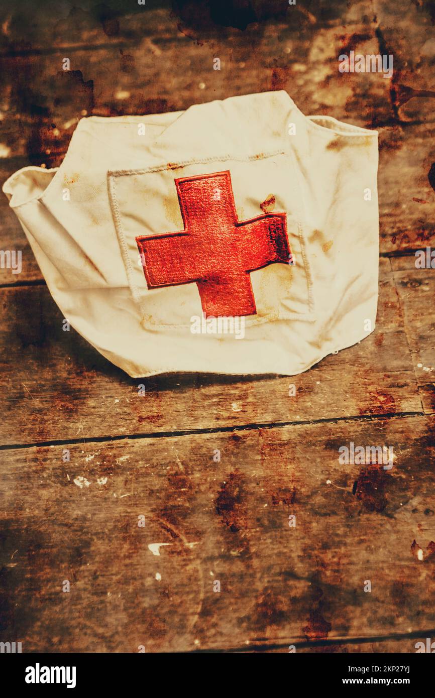 Vintage shot of nurse hat with red cross lying on wooden surface, WW2 ...