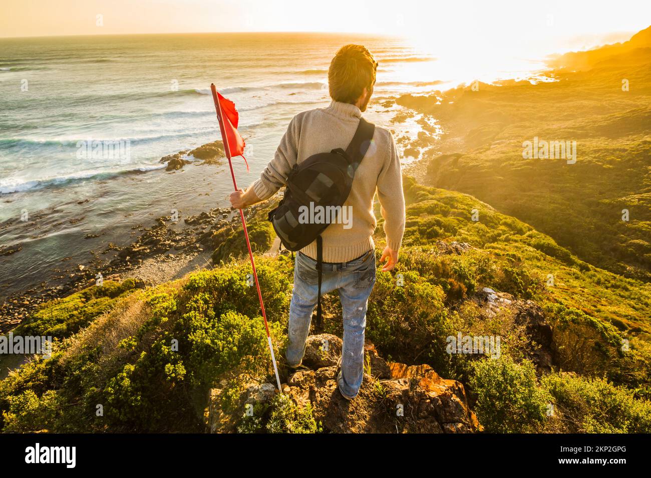 Horizontal lifestyle photo on a backpacker raising the flag of scenic ...