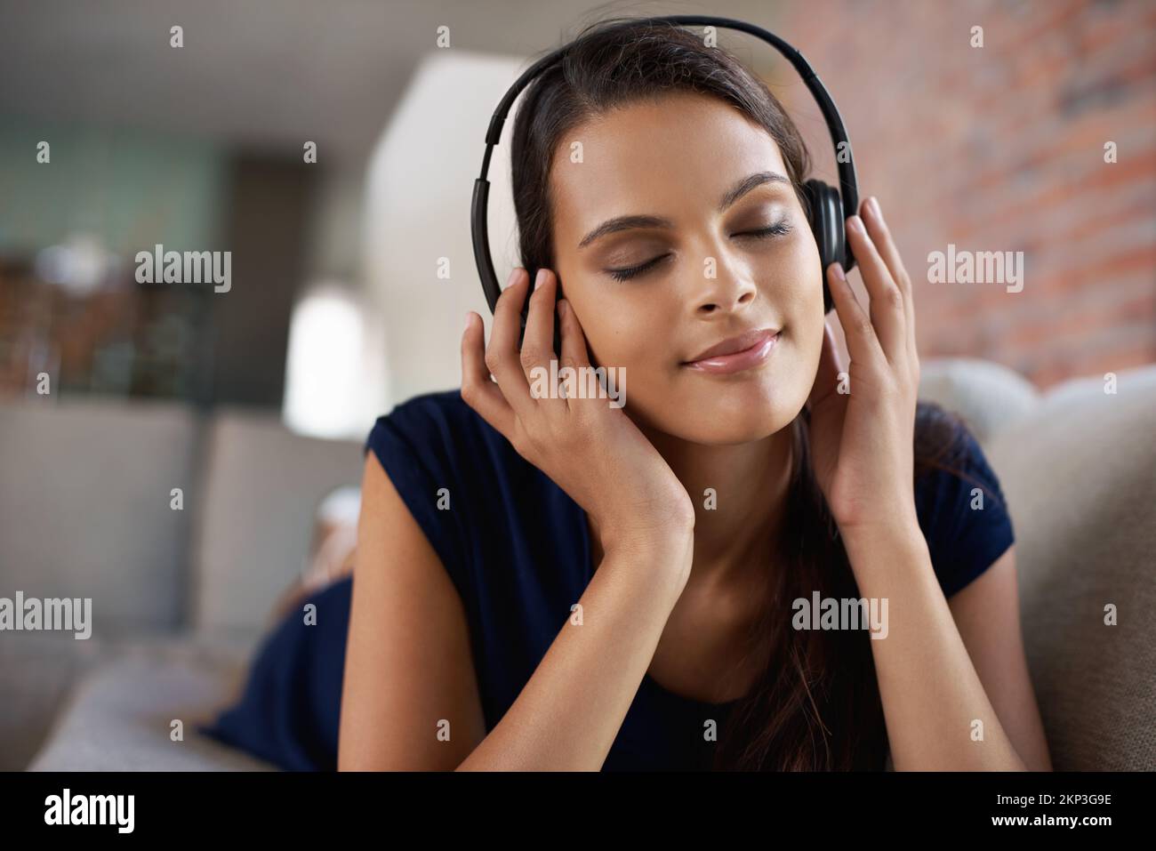 Music to relax to. a beautiful young woman lying on the sofa listening ...