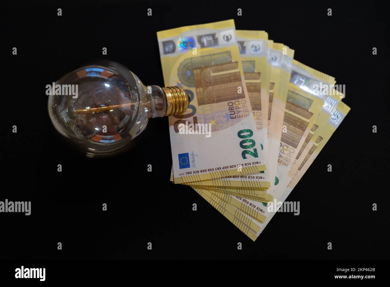 next to a old light bulb is a stack of 200 euro banknotes Stock Photo ...