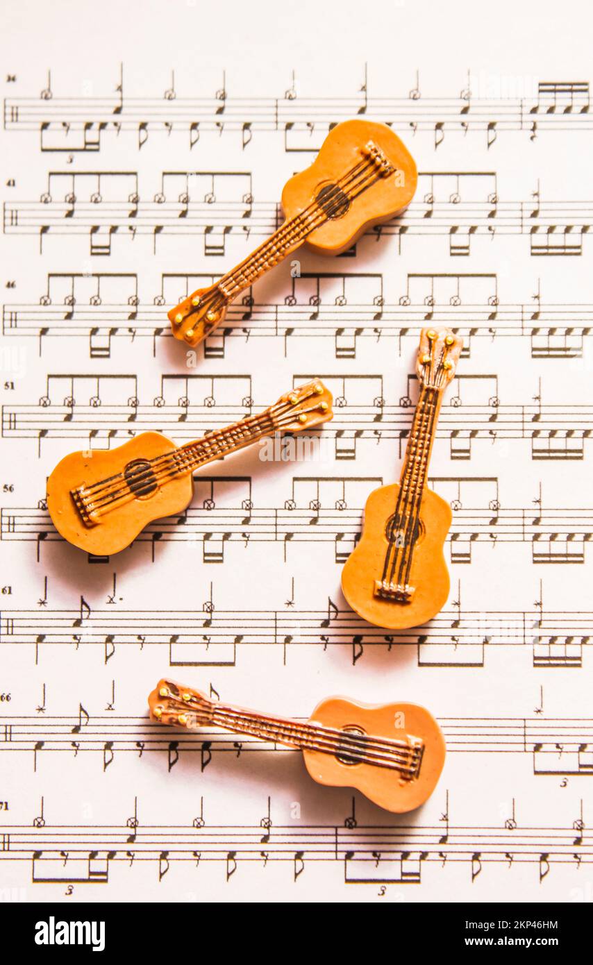 Quartet of four little country guitars on top of sheet music. Acoustic ...
