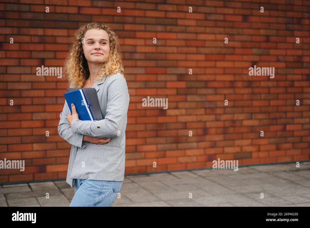 Happy beautiful student girl holding notebooks and laptop in her hand ...