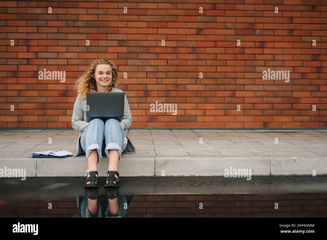 Happy smiling caucasian student girl sitting and working on her laptop ...
