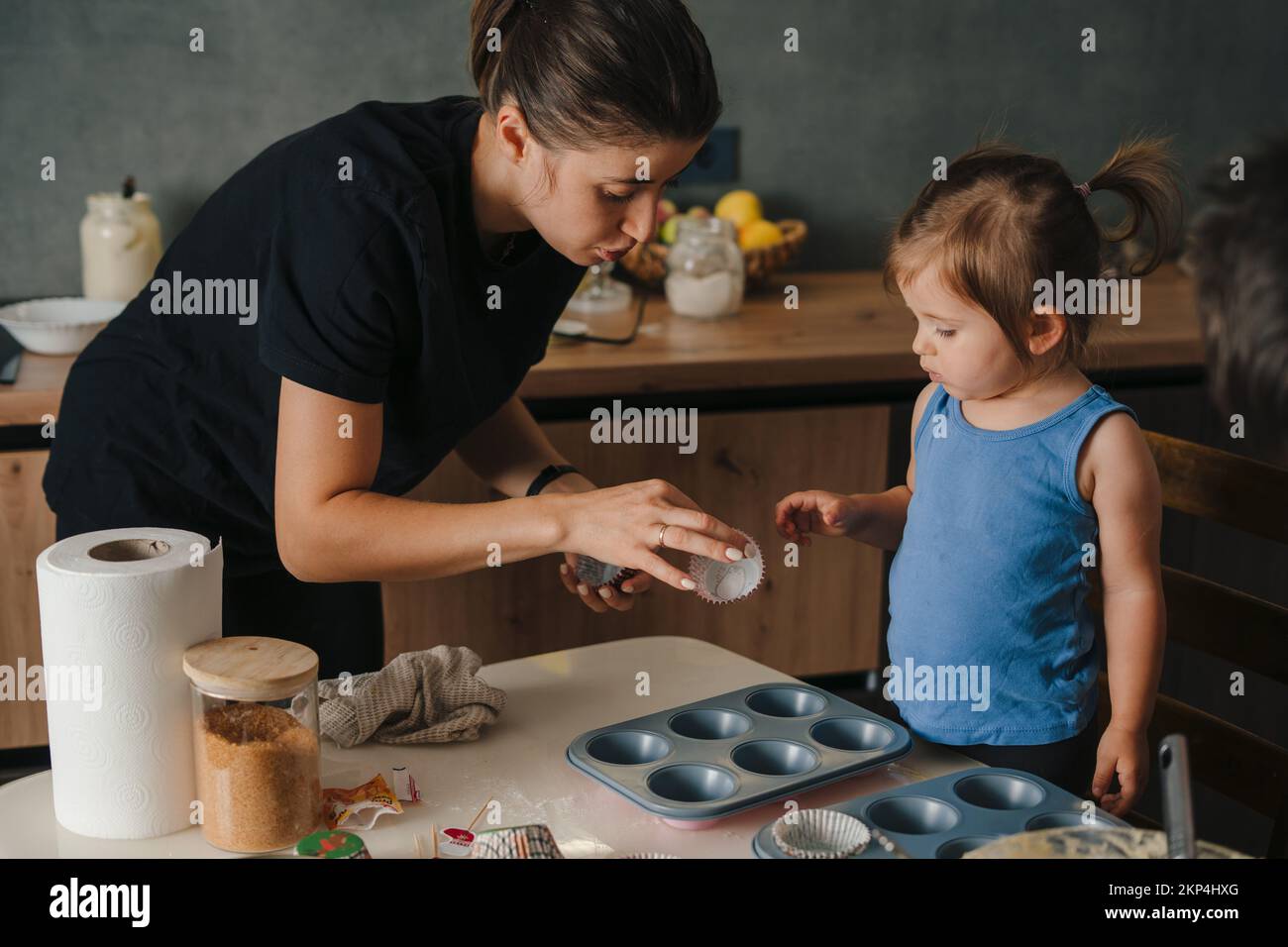 The mother showing the younger girl how to arrange the cooking forms to ...